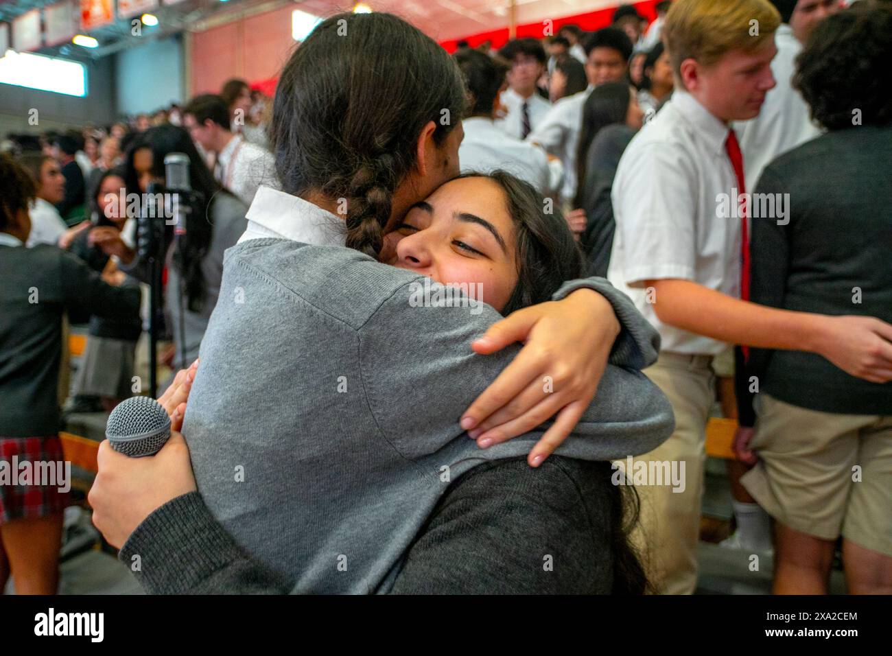 Multiracial uniformed students at a Southern California Catholic high school ceremonially hug ...