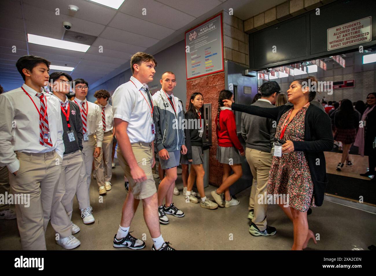 A teacher at a Southern California Catholic high school inspects multiracial students uniform ...