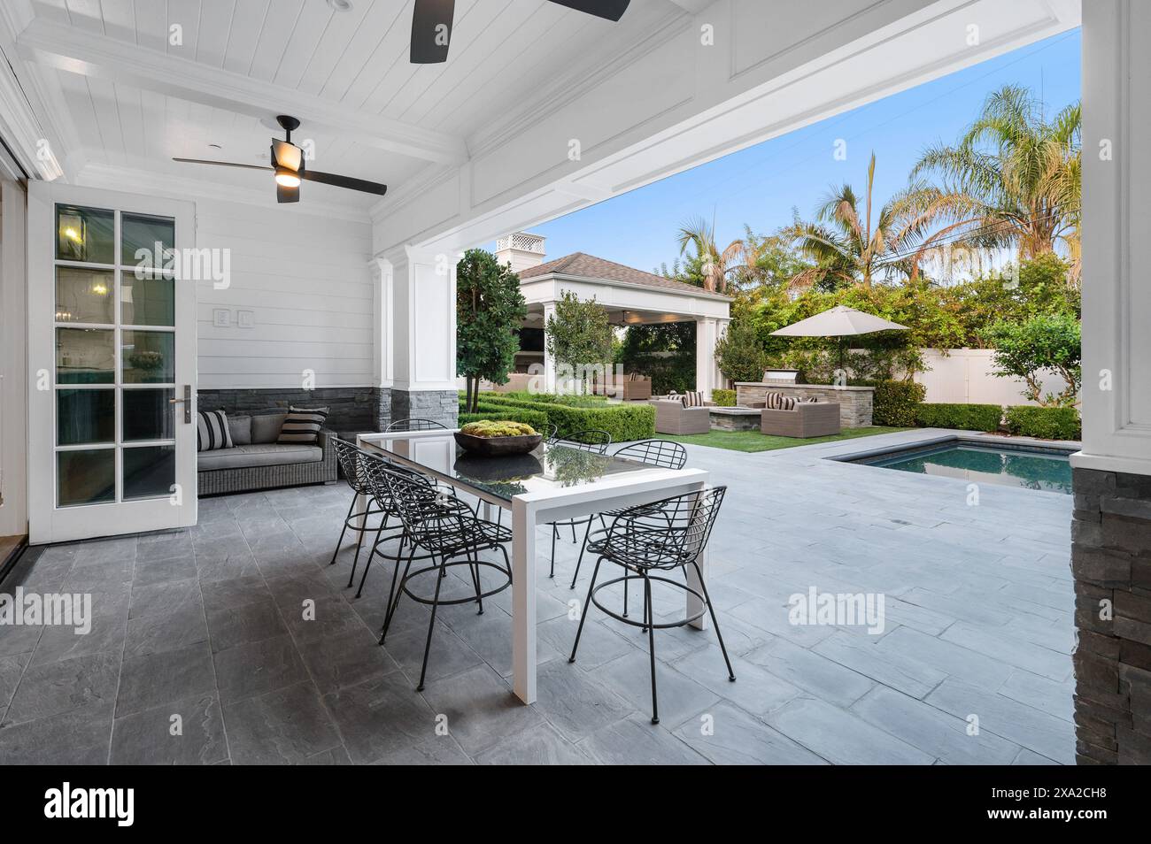 A poolside patio with outdoor dining table in a new construction home ...