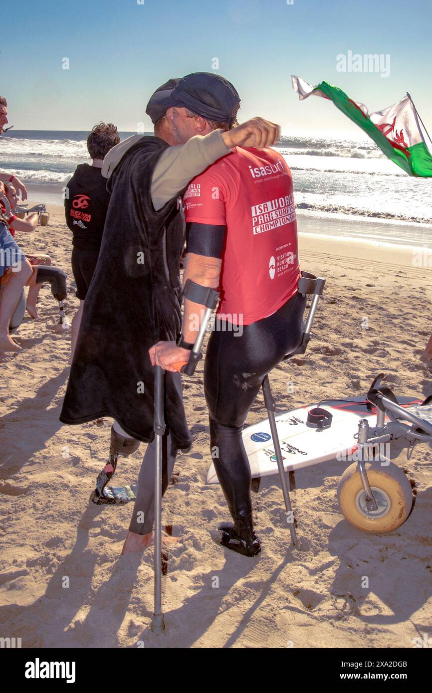 A parasurfer amputee uses crutches while a companion gives him a ...
