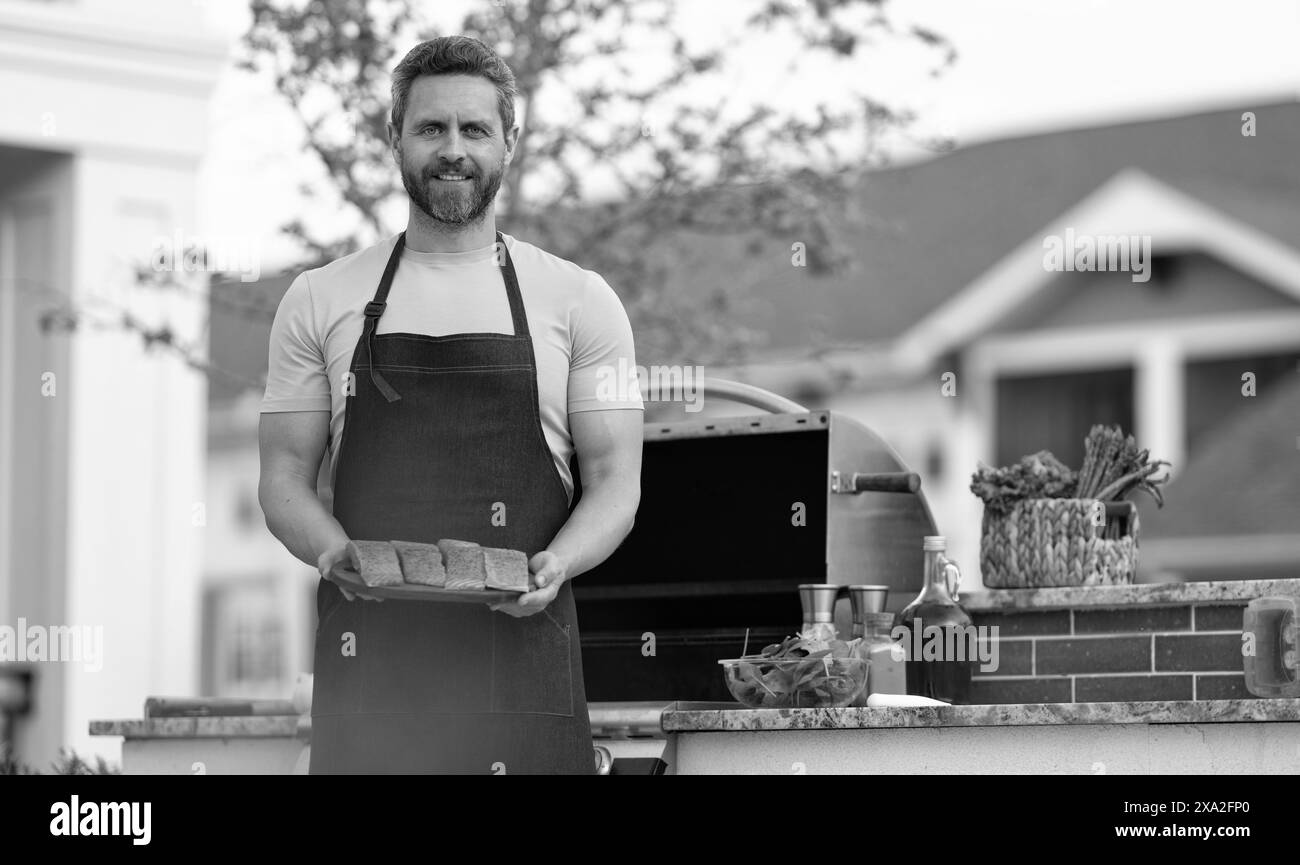 cheerful man cook salmon on grill. chef man cooking salmon on grill ...