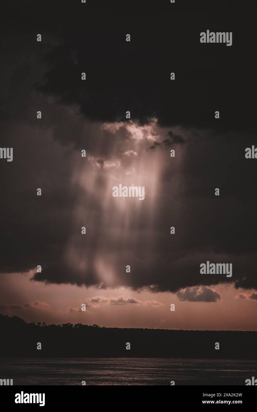 A captivating shot of sun rays piercing through dark storm clouds over the Zambezi River ...