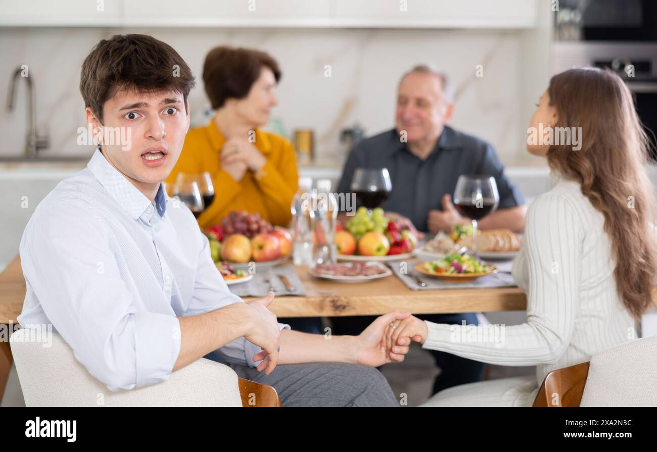 Shocked guy sitting at family dinner with comforting girlfriend Stock ...