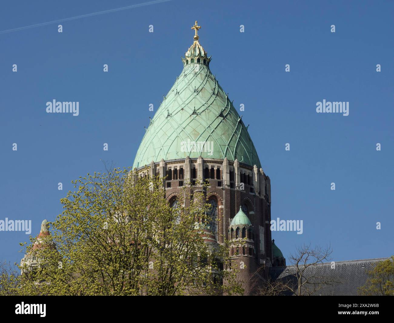 The upper part of a church tower with a greenish dome and a golden ...