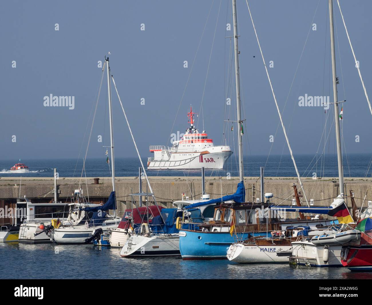 Harbour view with sailboats and a SAR rescue ship in the blue sea under ...