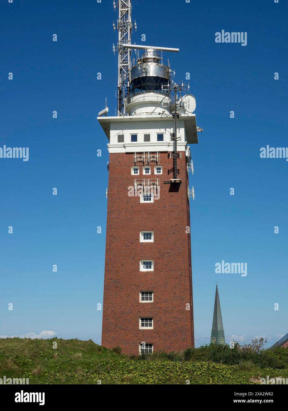 High brick lighthouse under blue sky with technical superstructures ...