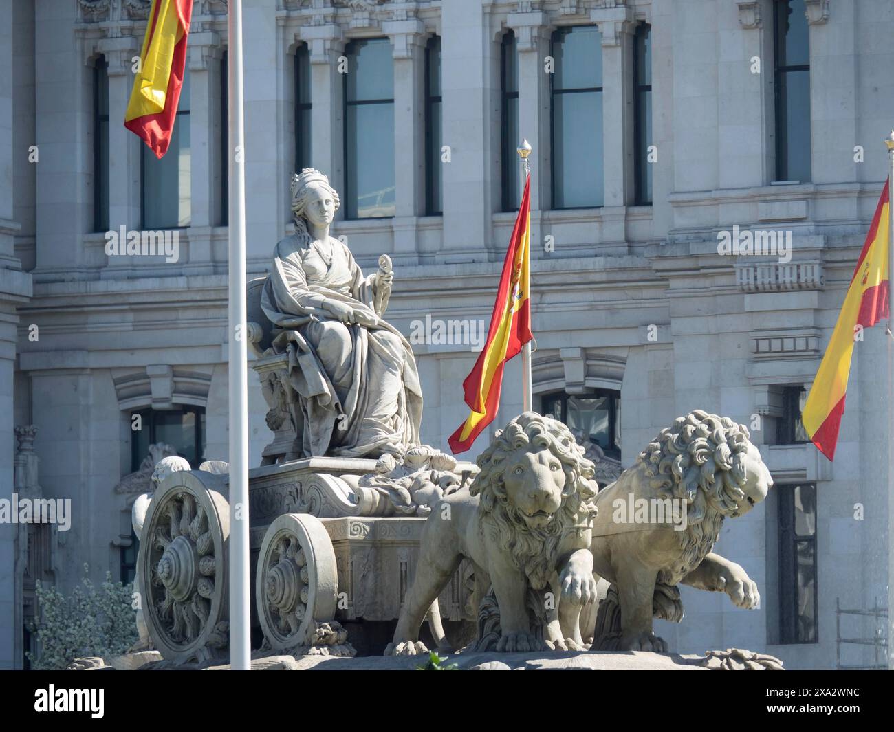 Historic fountain with a statue and two lions flanked by Spanish flags ...
