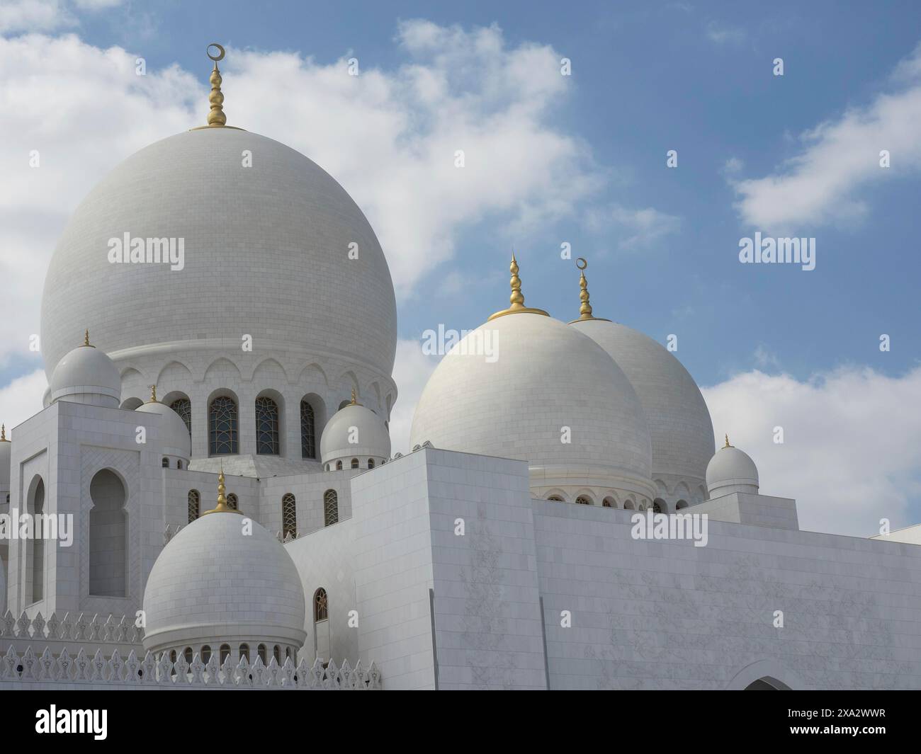 White domes of a mosque with golden jewellery under a blue sky ...