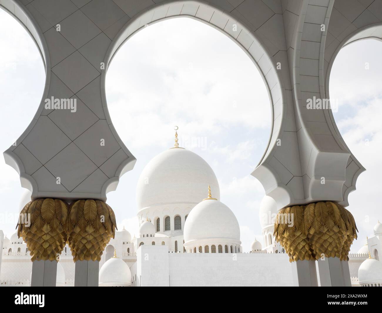 White and gold mosque with magnificent arches and domes, under a cloudy ...