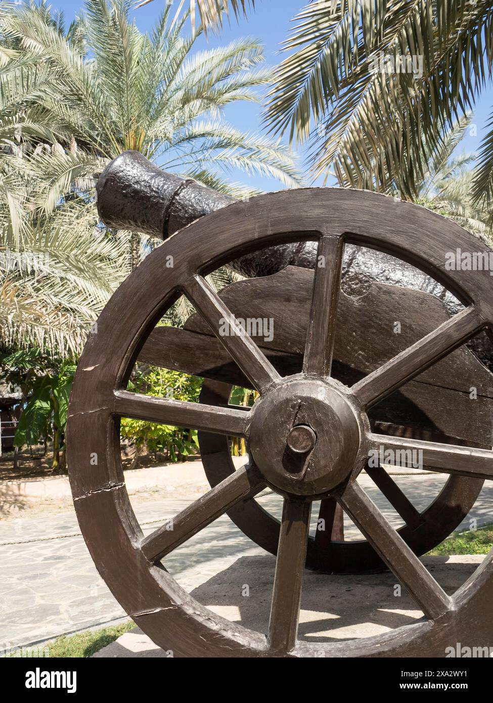 An old wooden cannon stands outside, surrounded by palm trees under a ...