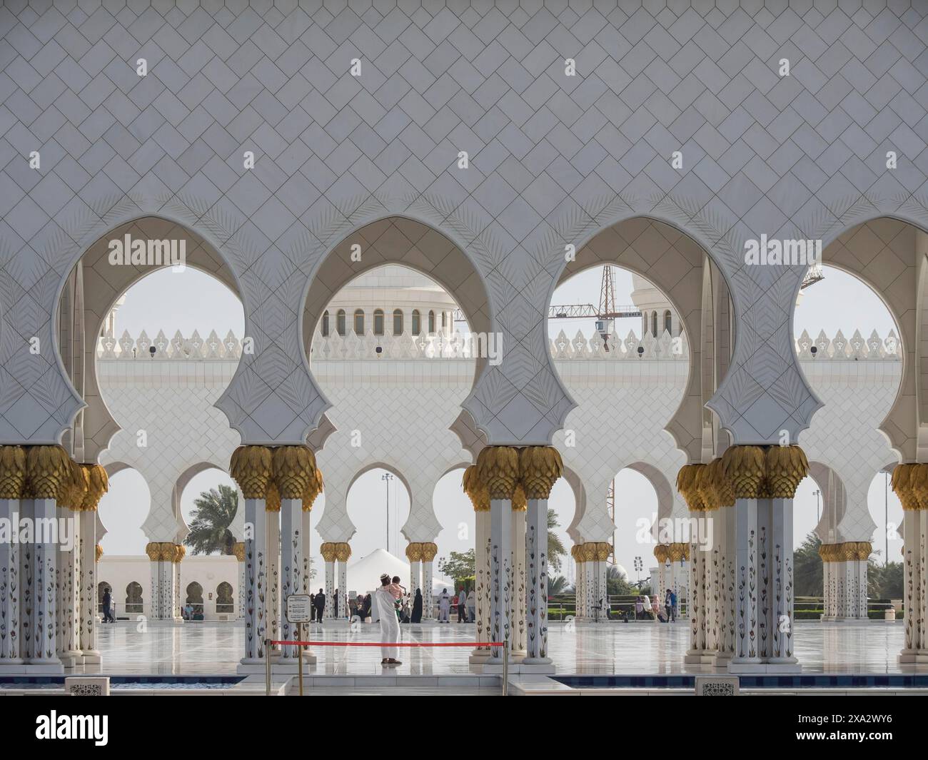 People pass elegant white arches with golden decorated columns in a ...
