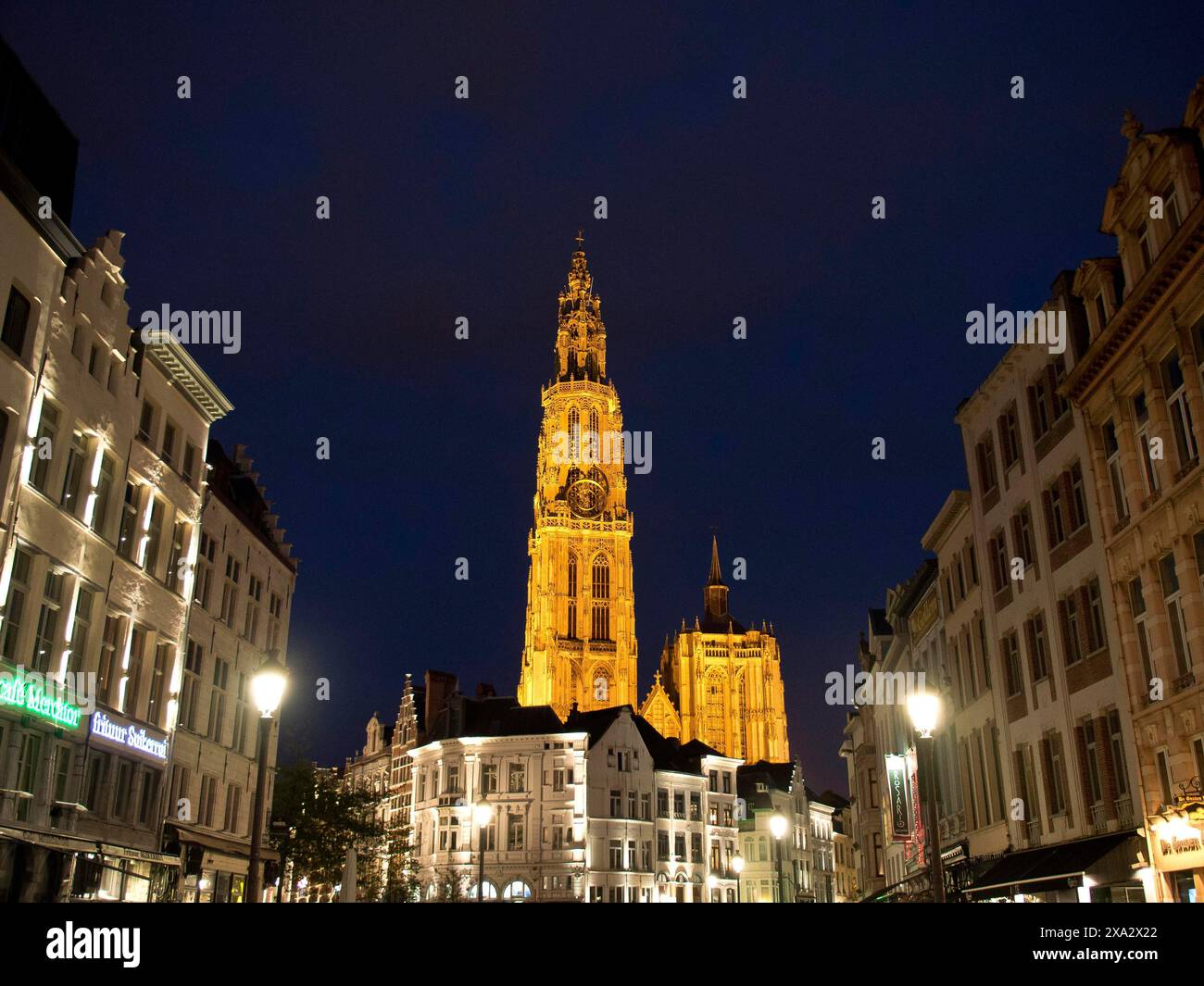 An imposing, illuminated church tower dominates the scenery of a lively ...