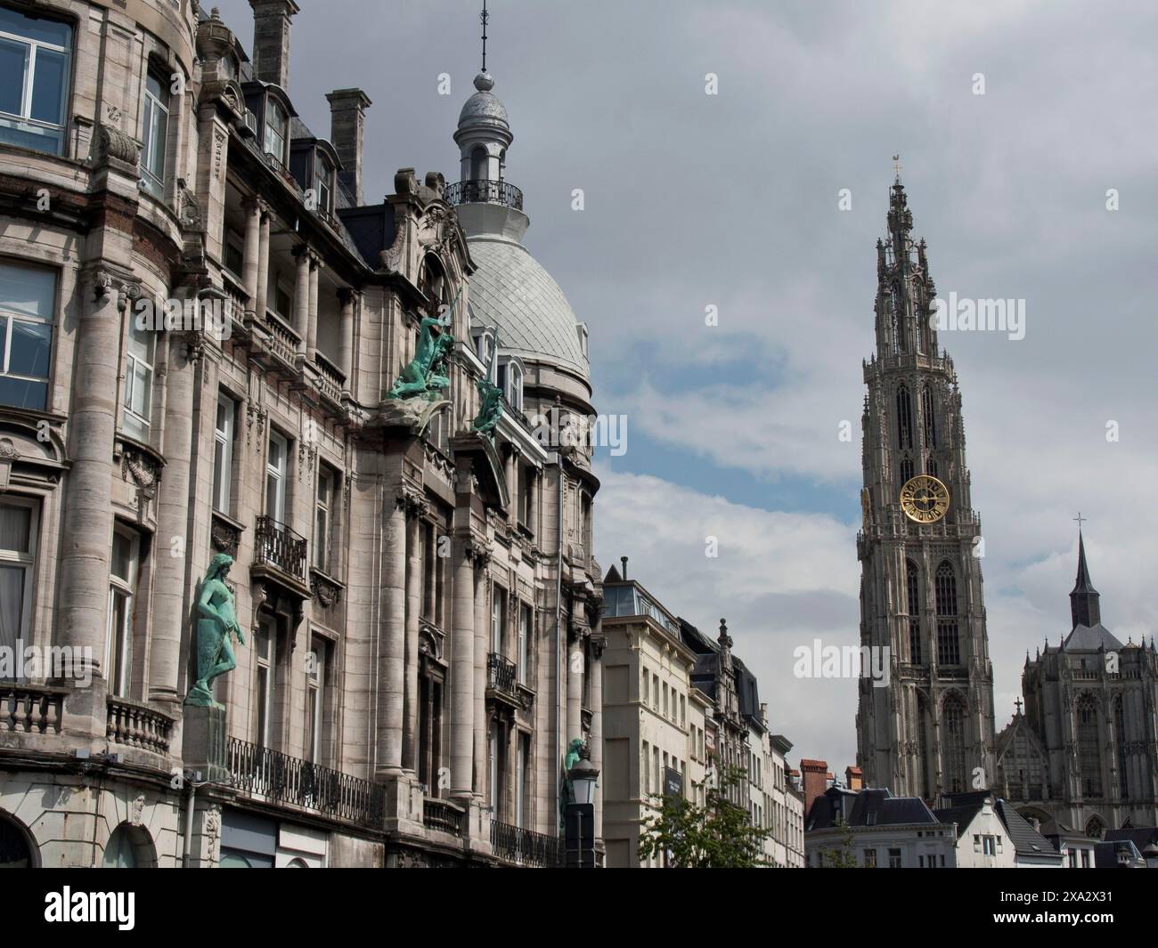 Historic street with decorative buildings and a large tower in the background, partly cloudy ...