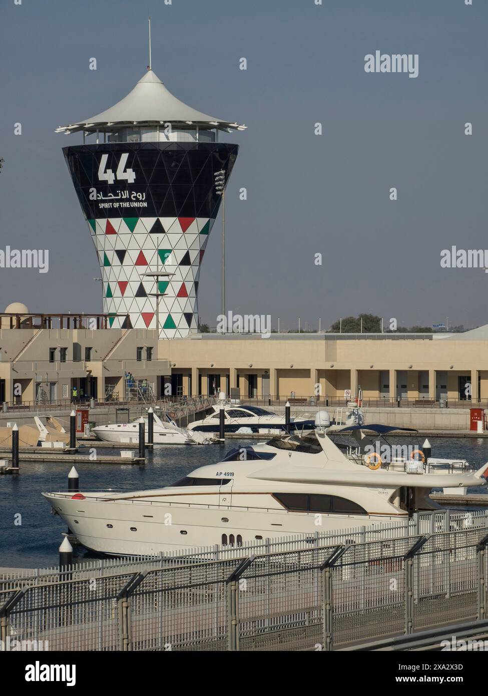A tall tower with a striking pattern stands in the harbour with yachts ...
