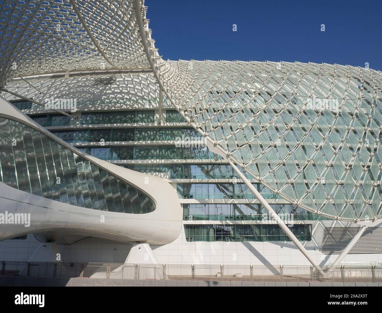 Building with a futuristic, curved glass facade and a clear sky behind ...