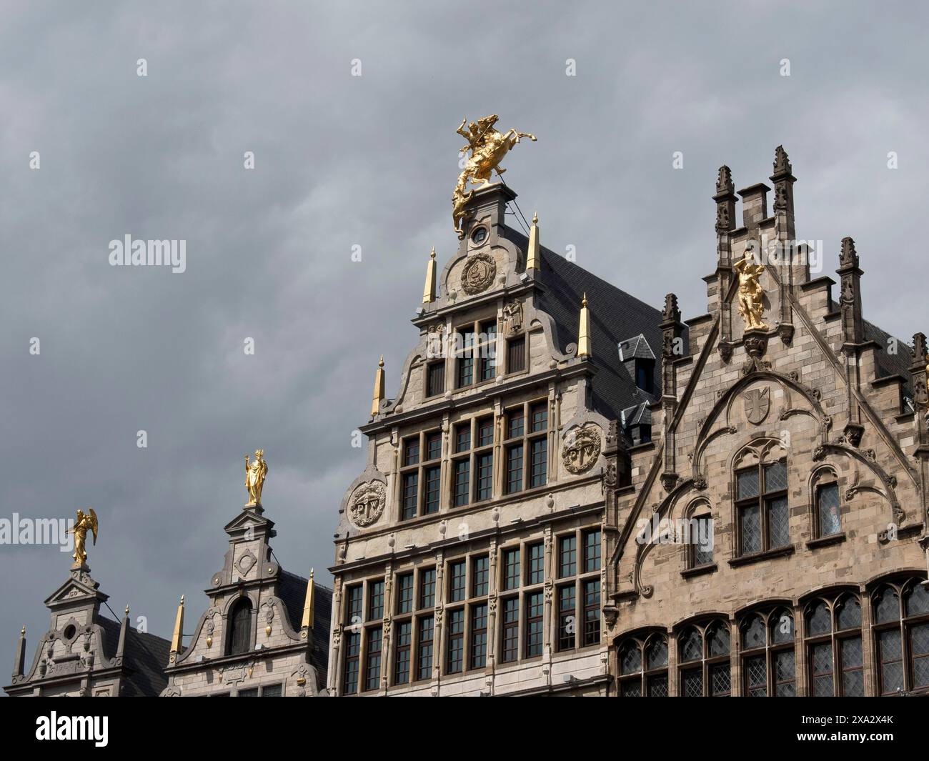 Historic buildings with golden statues on the roofs under a cloudy sky ...