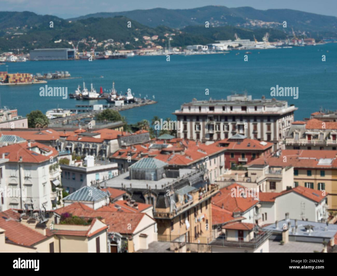 City view with red roofs, harbour, sea and surrounding hills on a clear ...