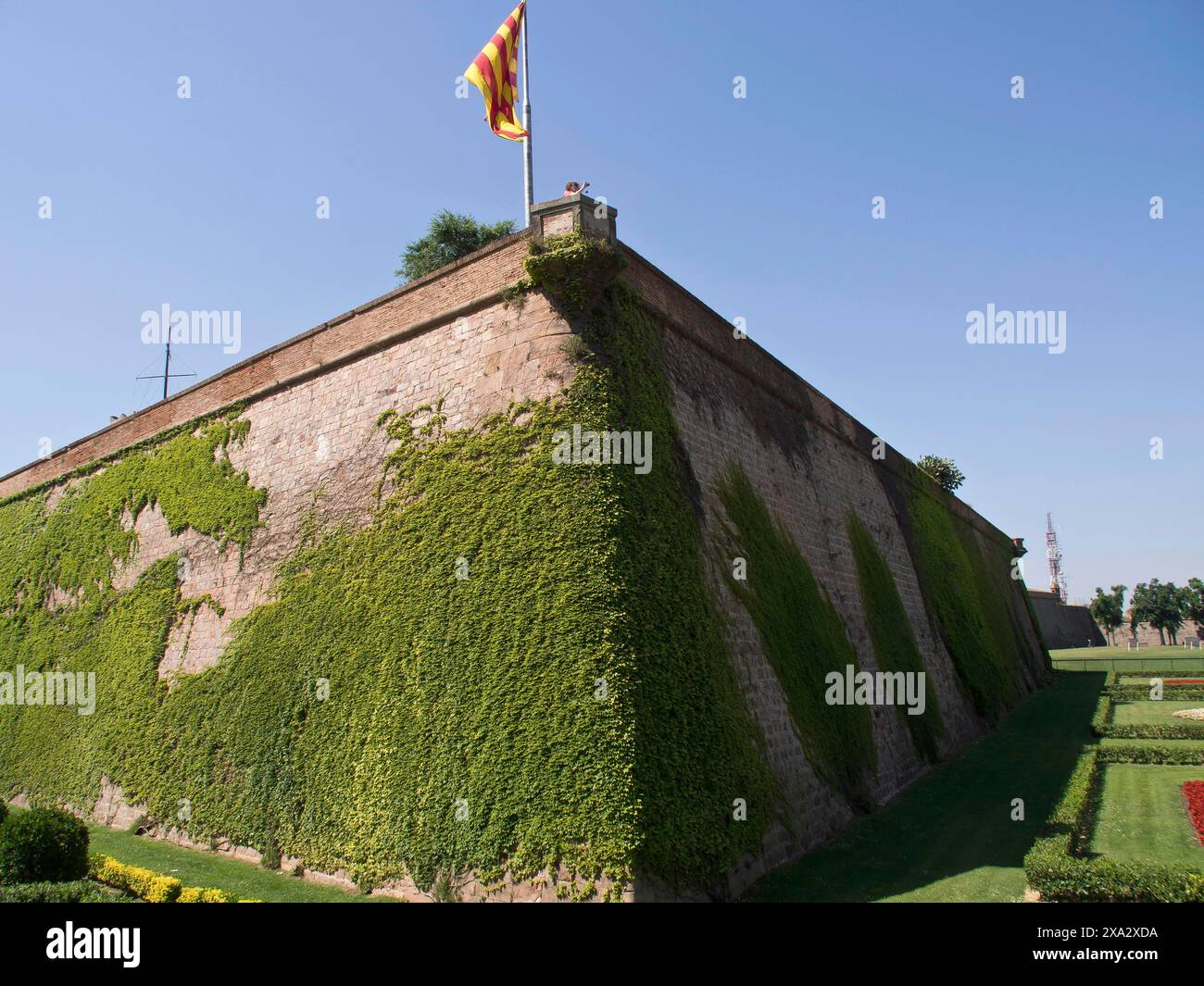 A fortress with high walls covered with climbing plants and a flag on ...