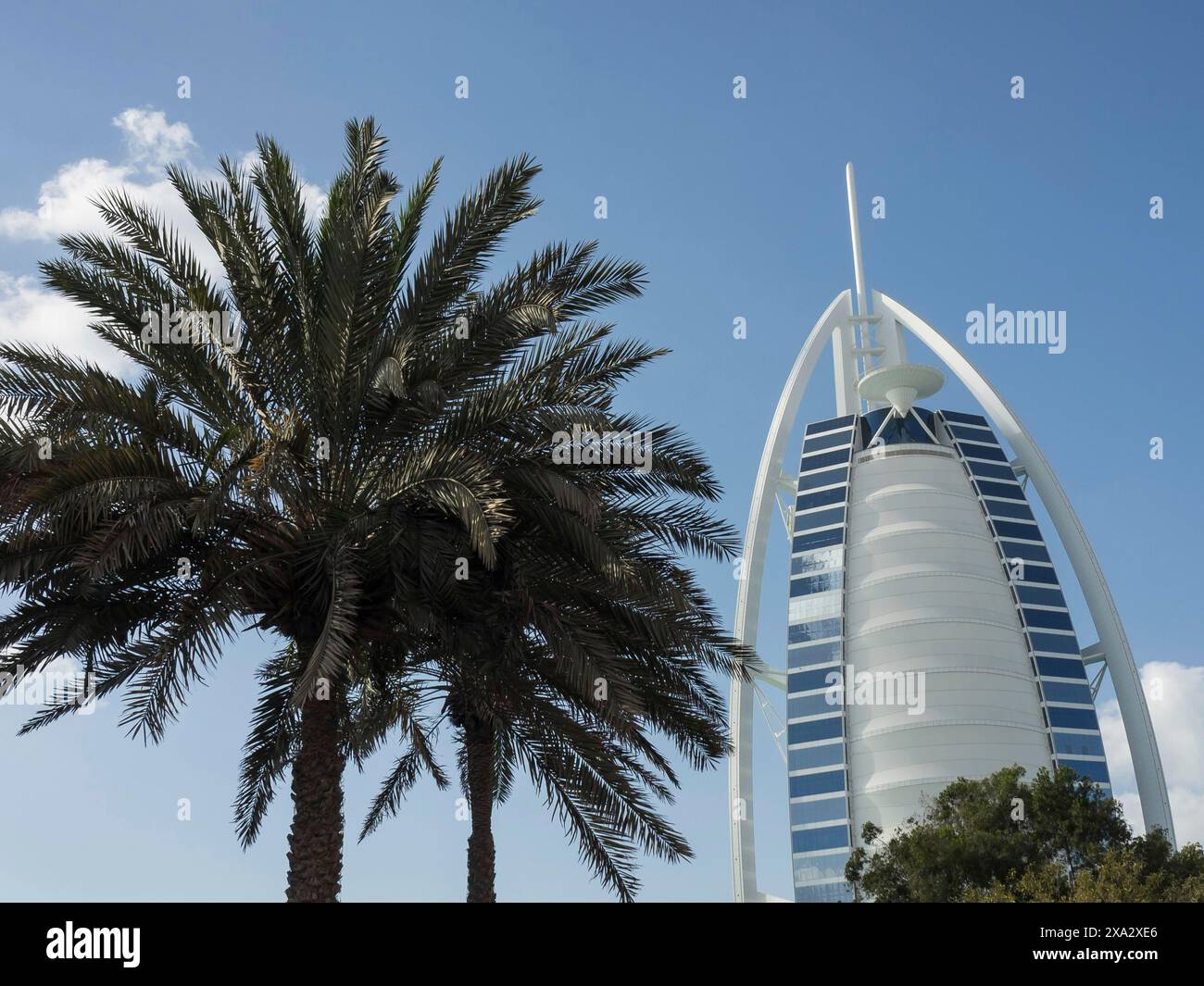 Burj Al Arab, a modern landmark, in front of a blue sky with a palm ...