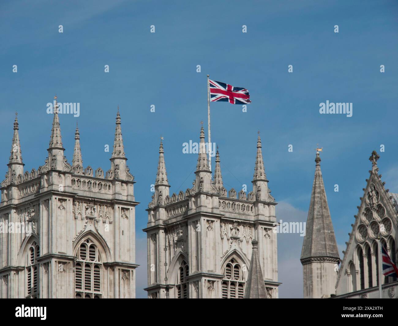 Several gothic towers with a British flag waving against a blue sky ...
