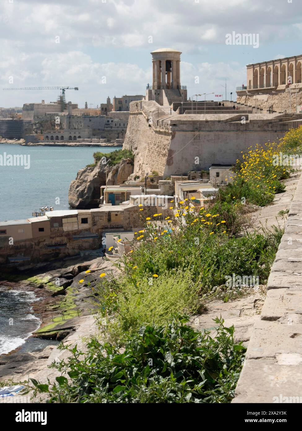 Coastal view of an old town with flowers and wall by the sea, blue sky ...