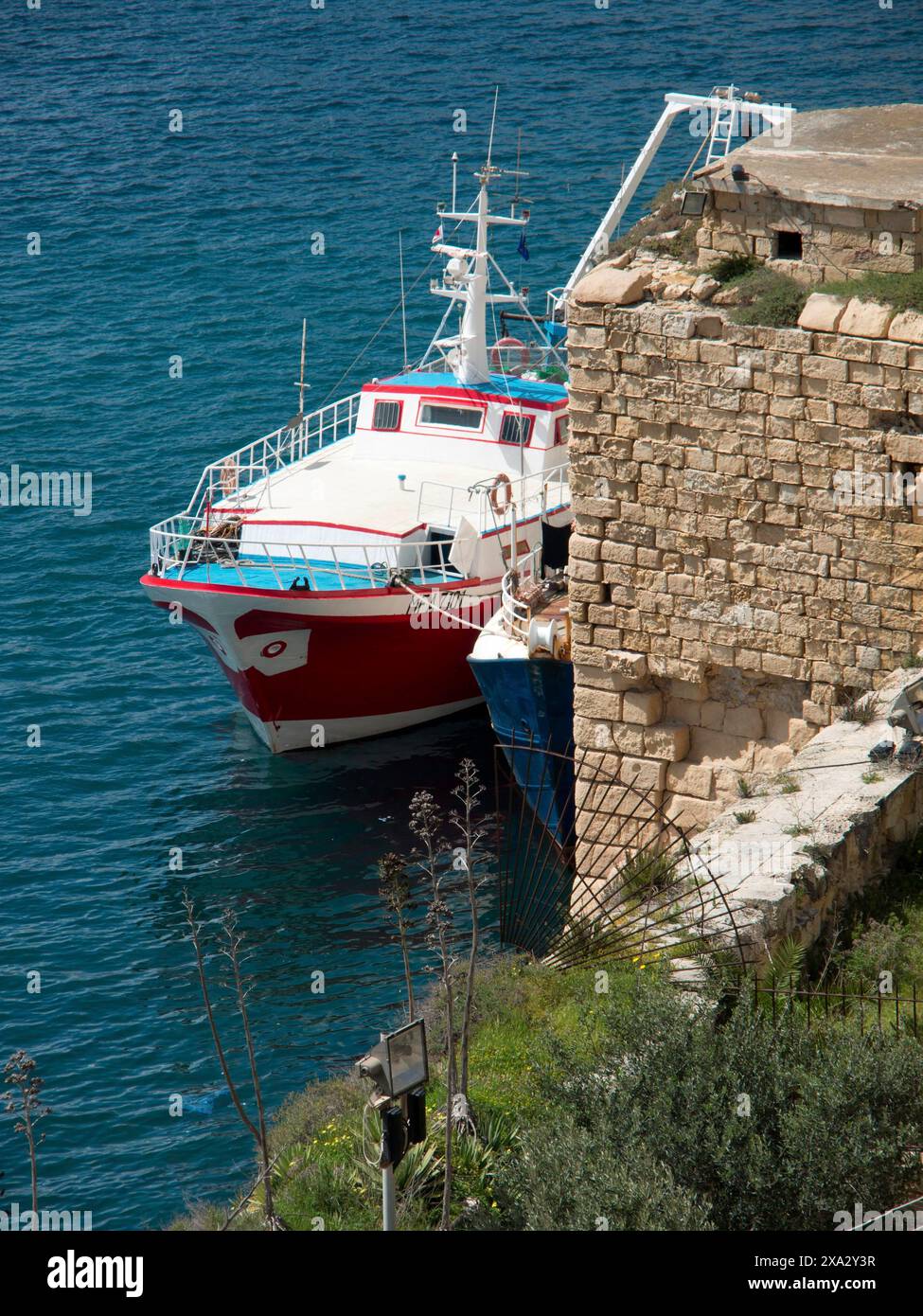 Red and white fishing boat and stone structure at the harbour, Valetta ...