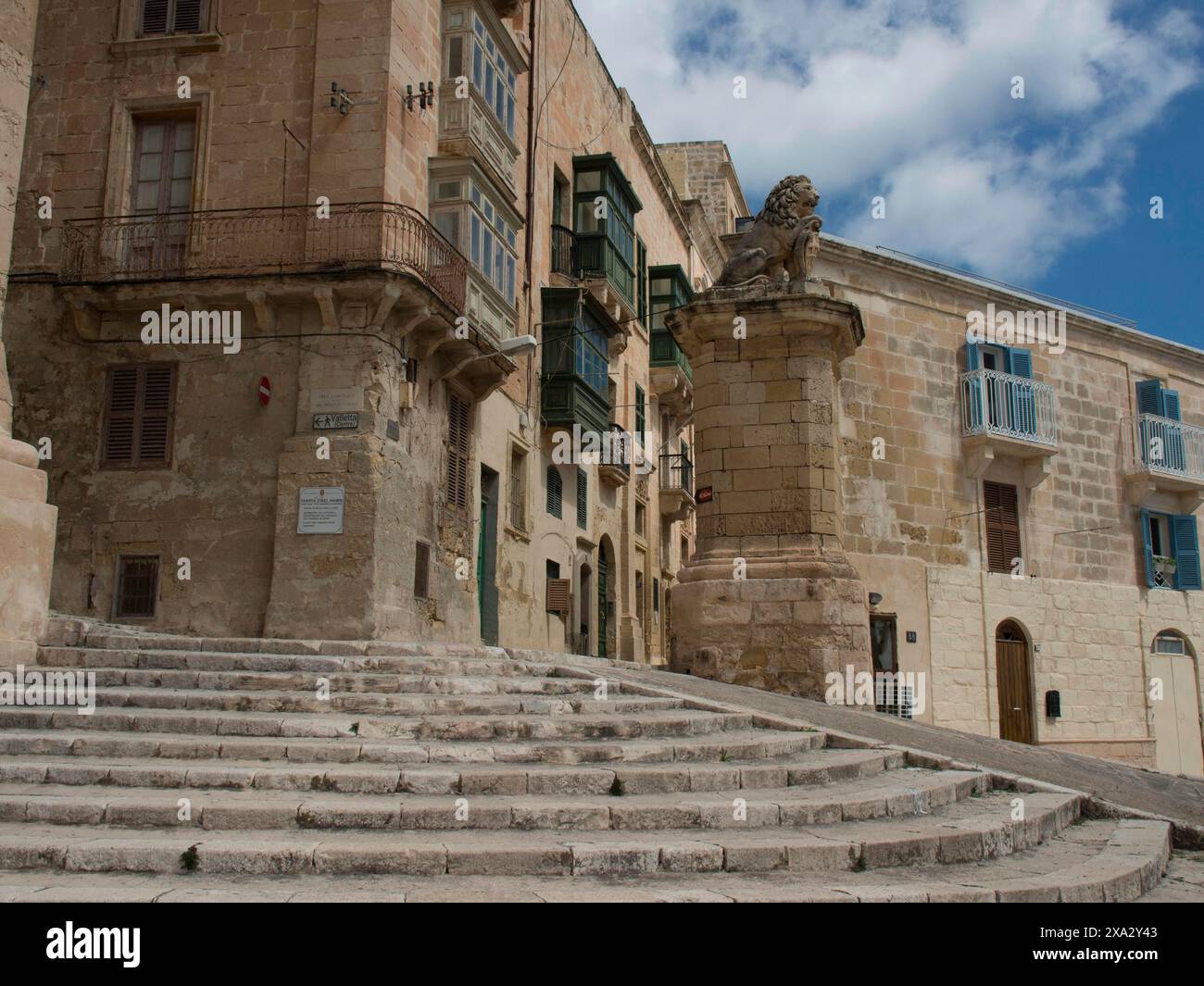Stone steps lead to historic buildings under a blue sky, Valetta, Malta ...