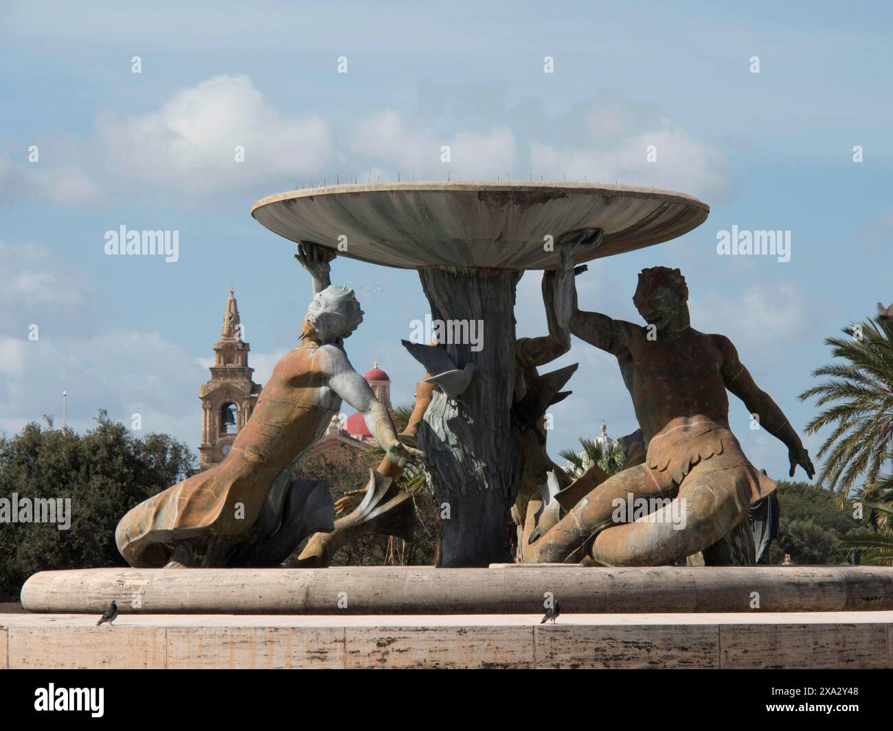 Two statues holding a fountain in an ornate park under a bright blue ...