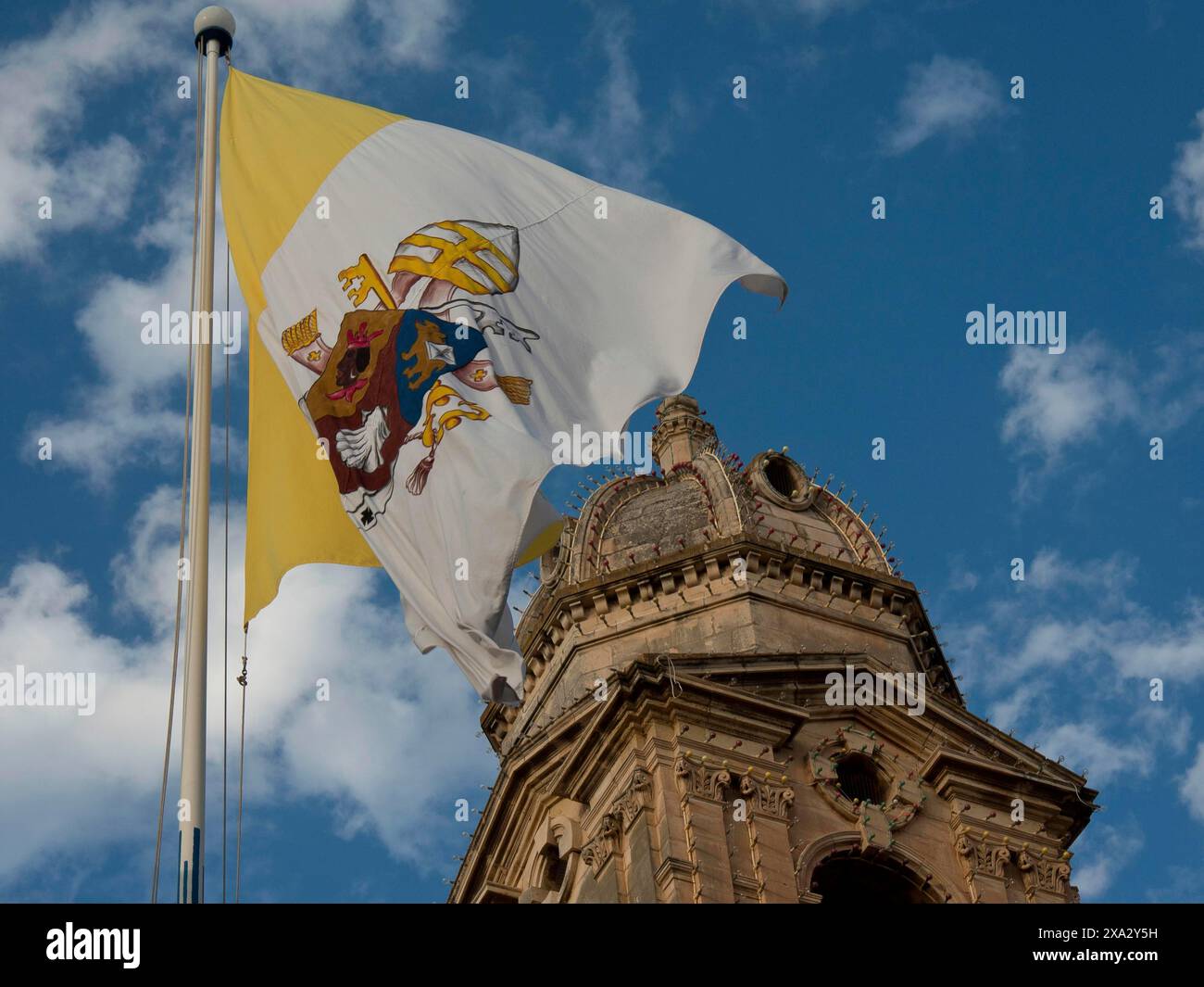 Yellow and white flag with symbols waving in the wind in front of a ...