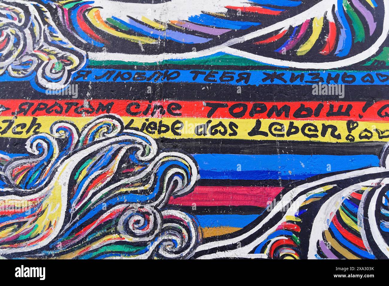 Colourful graffiti waves with texts in different languages on a wall ...