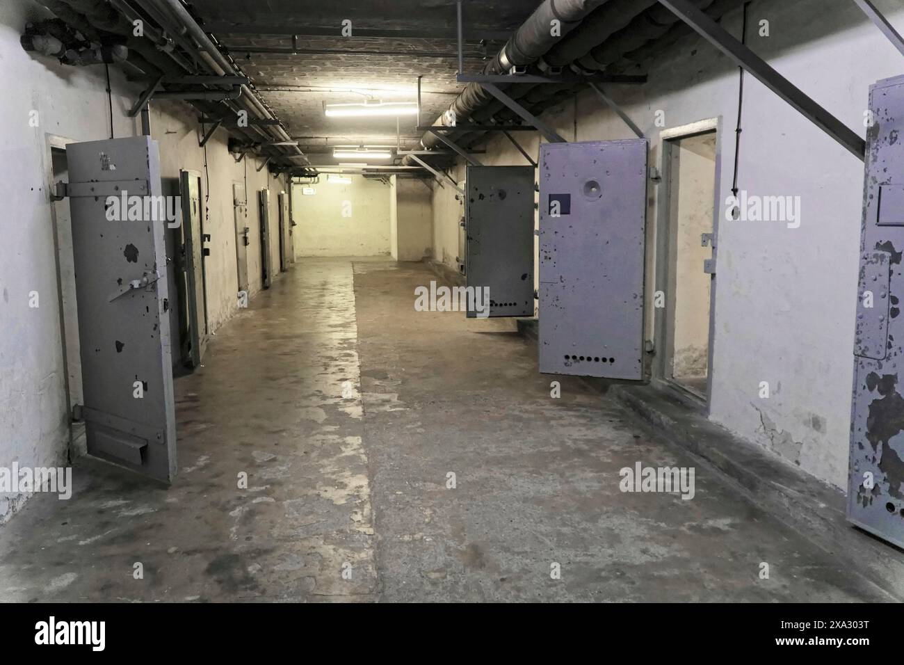 Long prison corridor with open metal doors and grey walls. Gloomy ...