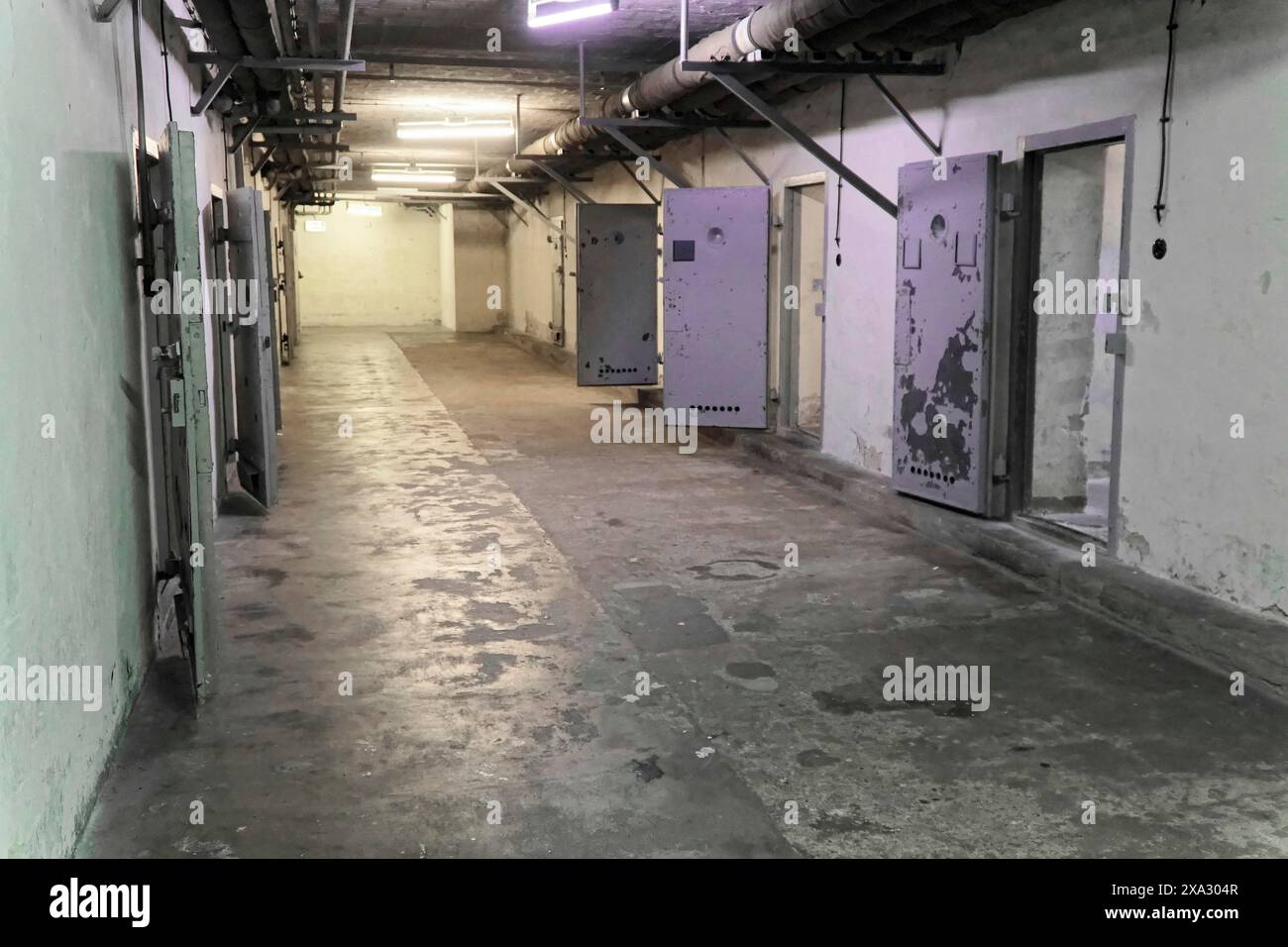 Long corridor in a prison with open metal doors and dirty walls. Cold ...