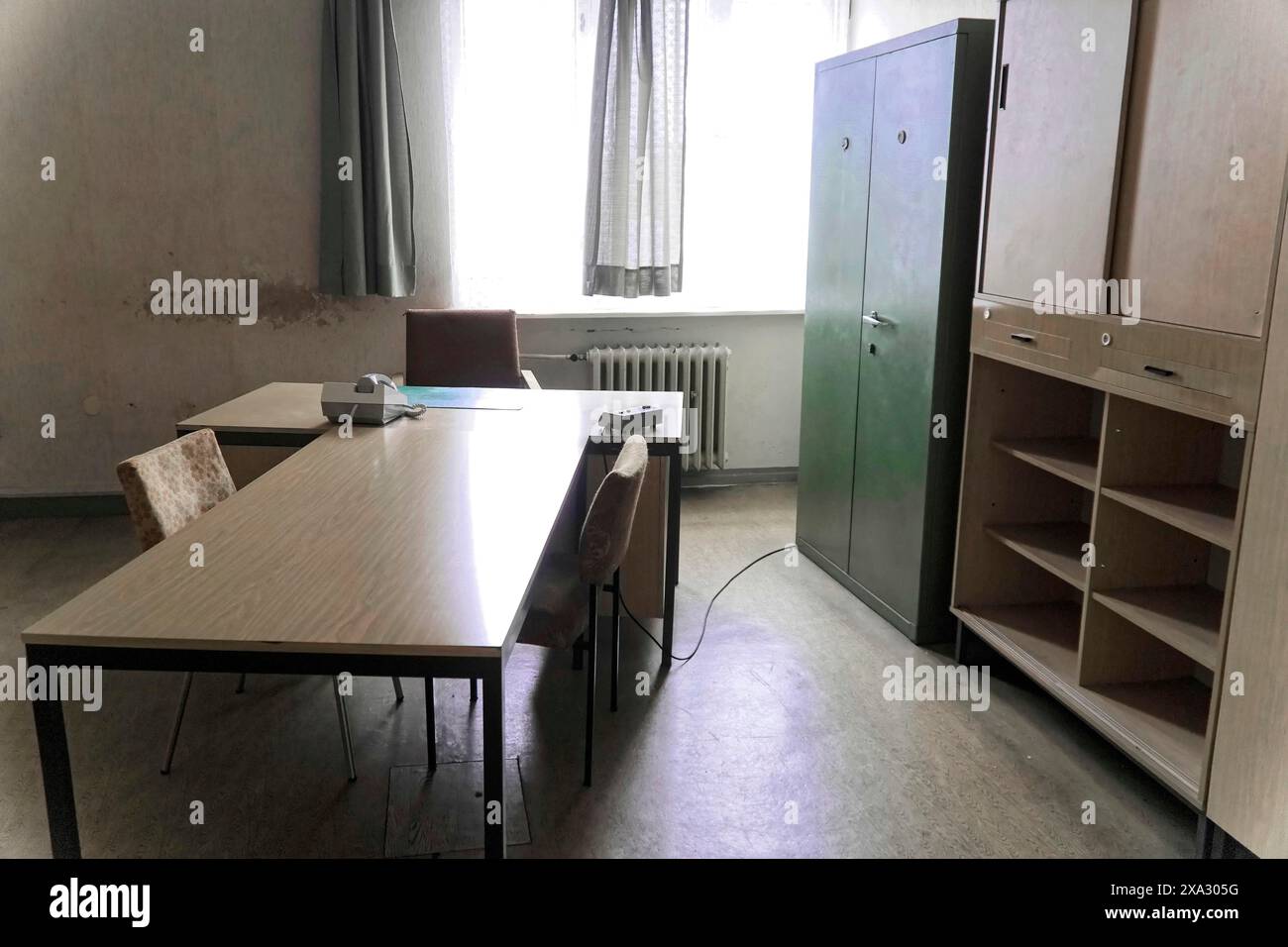 An office with simple furniture, desk, chairs, filing cabinet and a ...