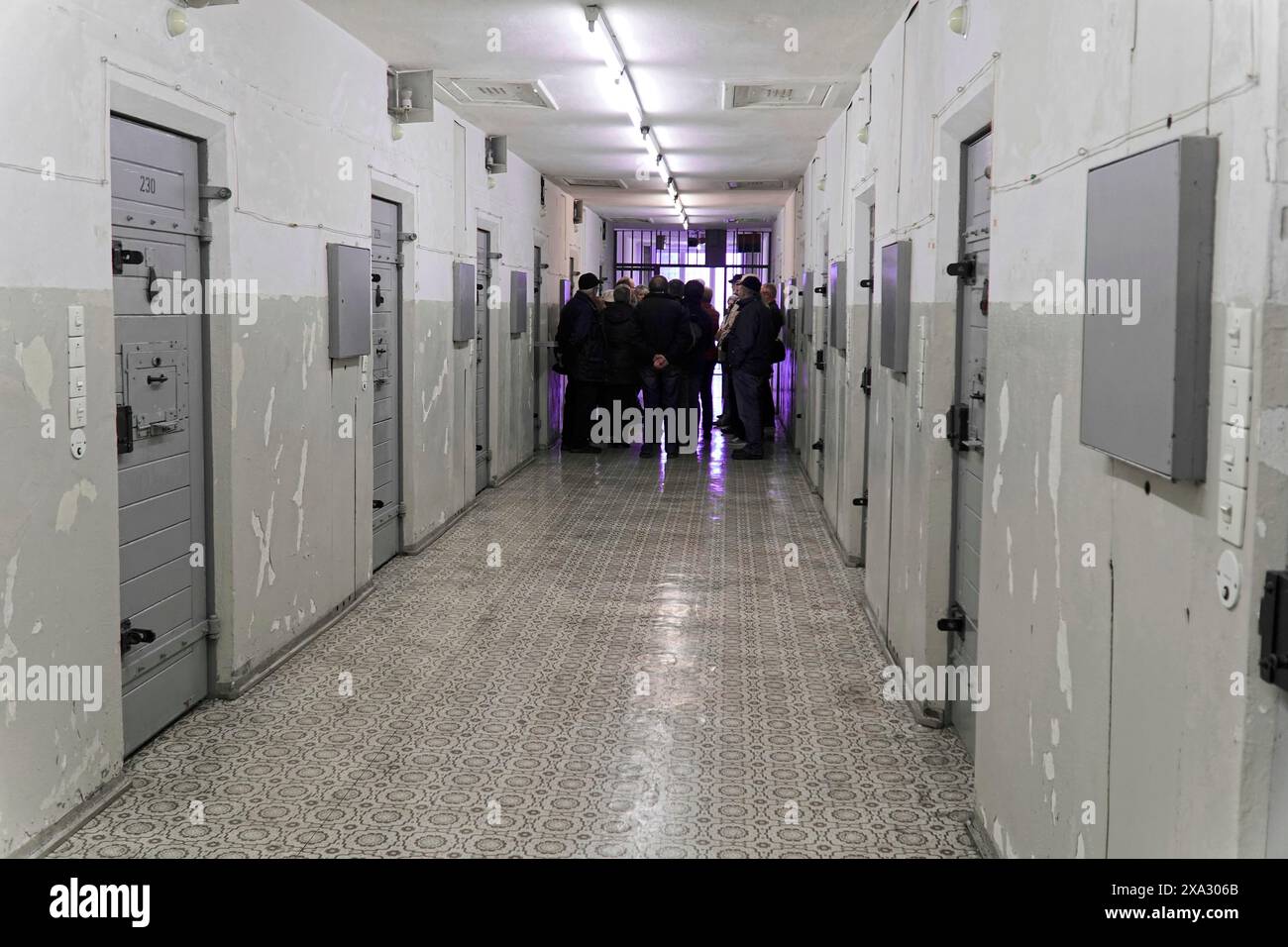 Group of people in the corridor of a prison with grey doors and neon ...