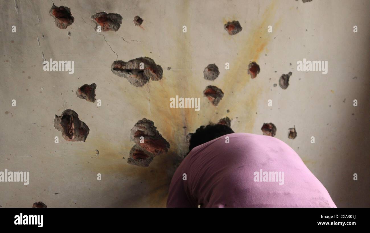 A man facing a wall riddled with bullet holes, sign of destruction in ...