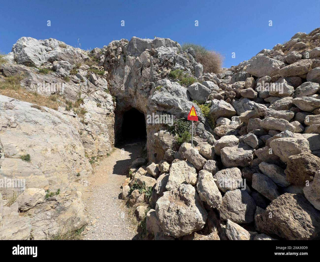 Entrance of a developed cave next to a warning sign warning of falling ...