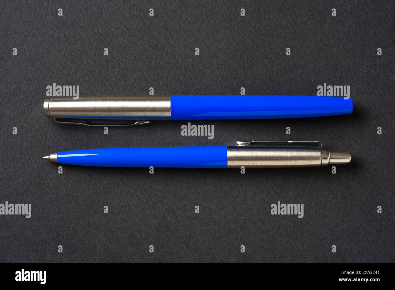 Blue plastic and metal ballpoint pen and fountain pen on dark gray ...