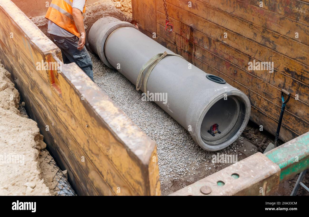 Builder installing big diameter concrete drainage pipe protected by ...