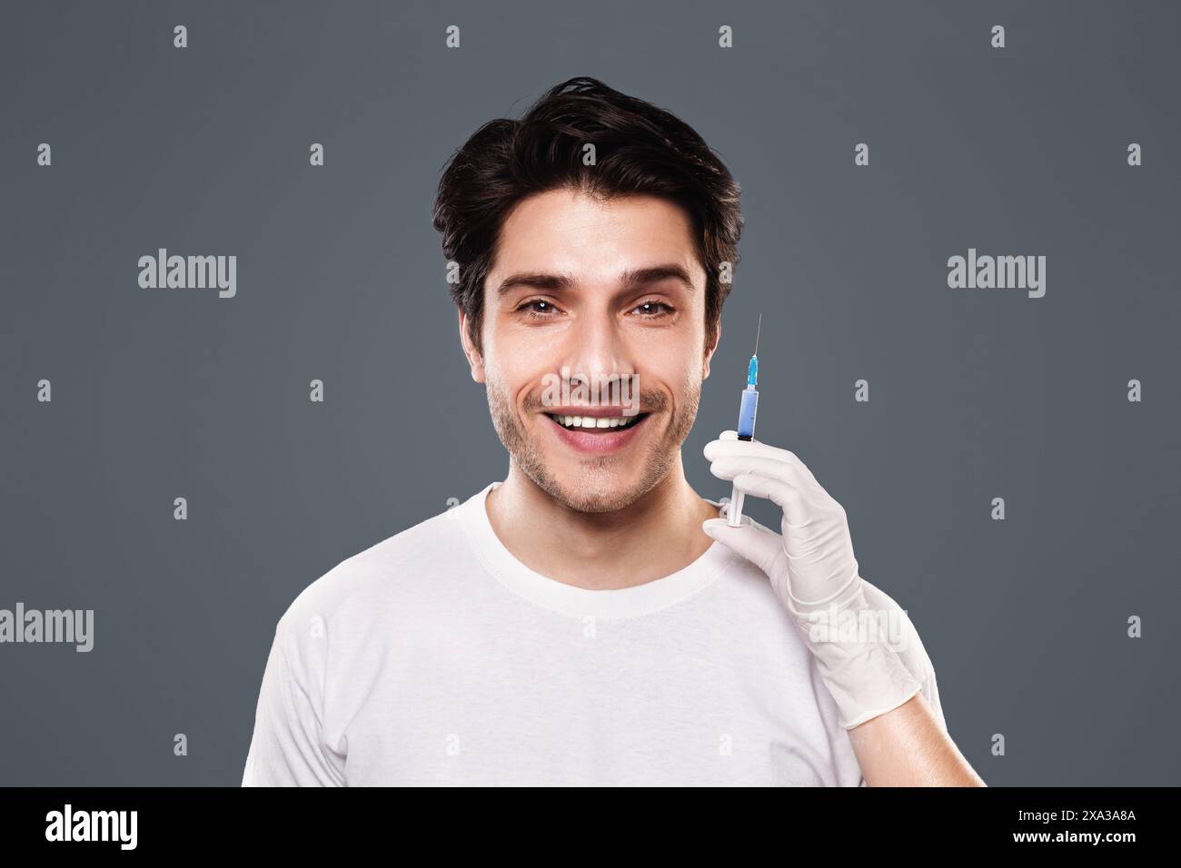 Young man getting beauty injection, grey studio background Stock Photo ...