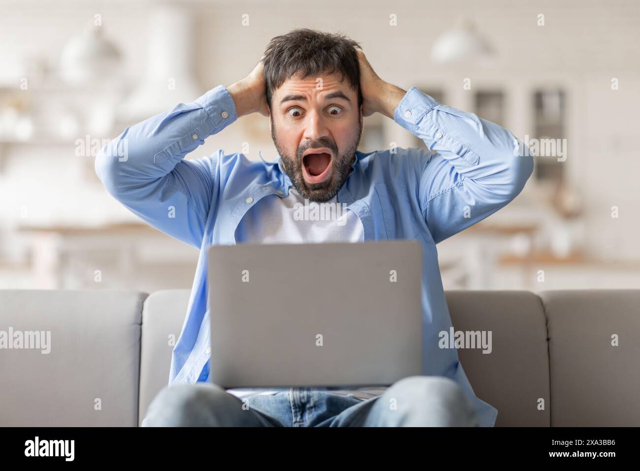 Shocked Man Reacting to Laptop Screen While Sitting on Couch Stock ...
