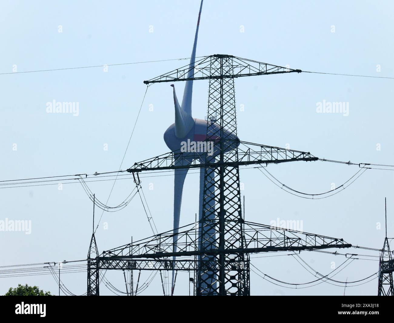 A photo of a wind turbine and a high voltage mast symbolizes ...