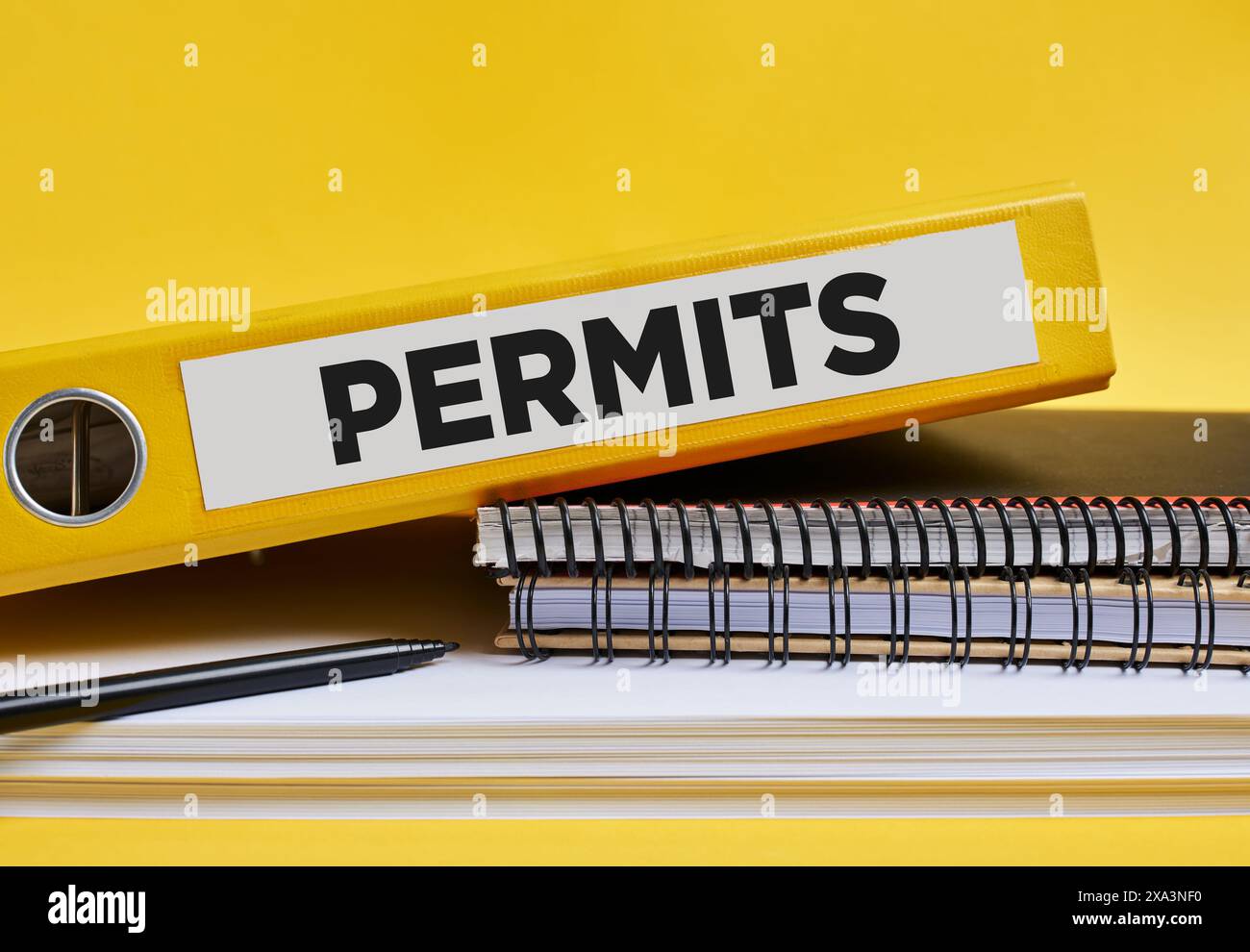 The word permits written on the label of a yellow binder on the office ...