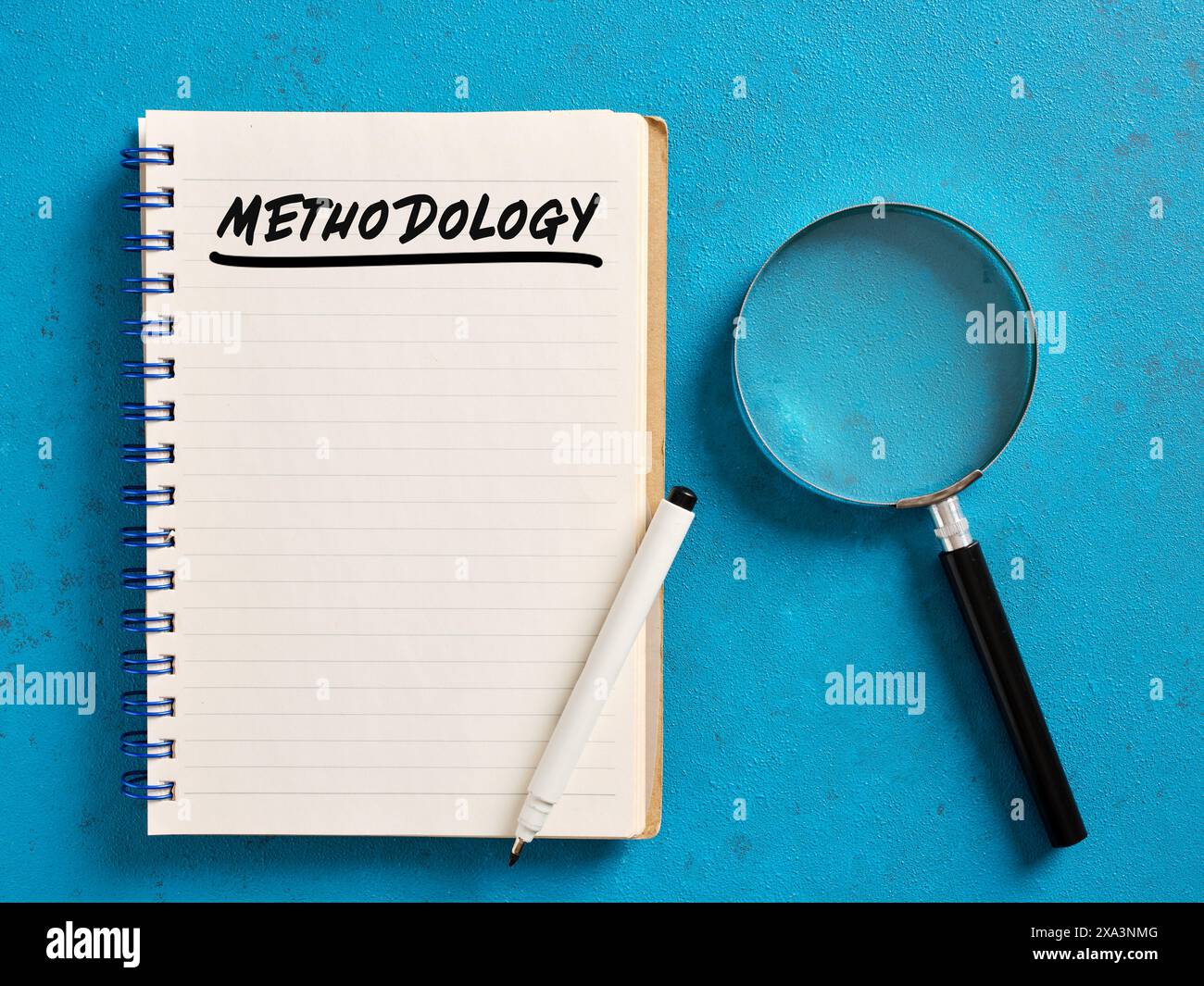 The word methodology handwritten on a notebook with a magnifying glass ...
