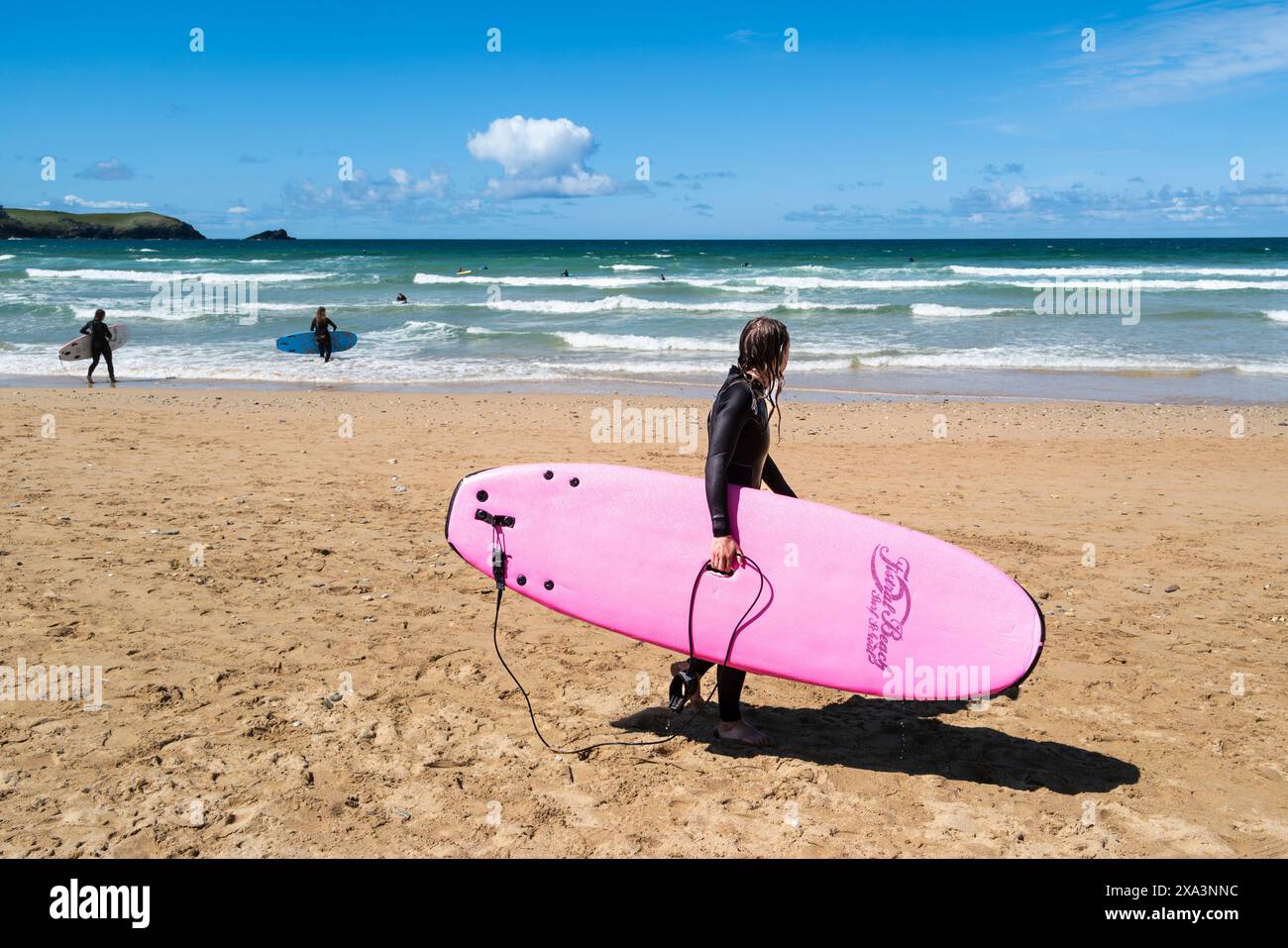 A female surfer carrying her surfboard after surfing at Fistral Beach ...