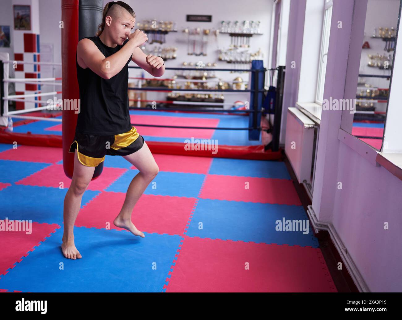 Young teenage kickbox fighter doing shadow boxing drills in a gym as ...