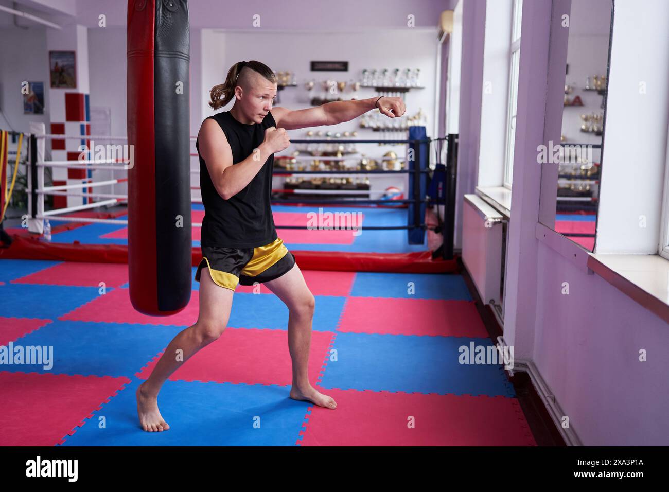 Young teenage kickbox fighter doing shadow boxing drills in a gym as ...
