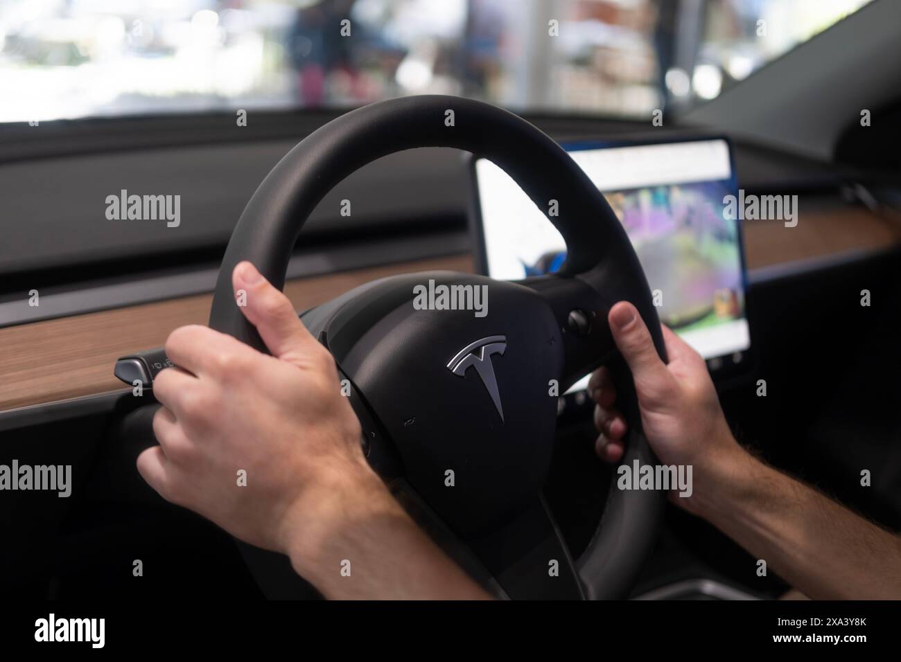 Behind steering wheel Tesla model Y electric car, male hands on Driver ...