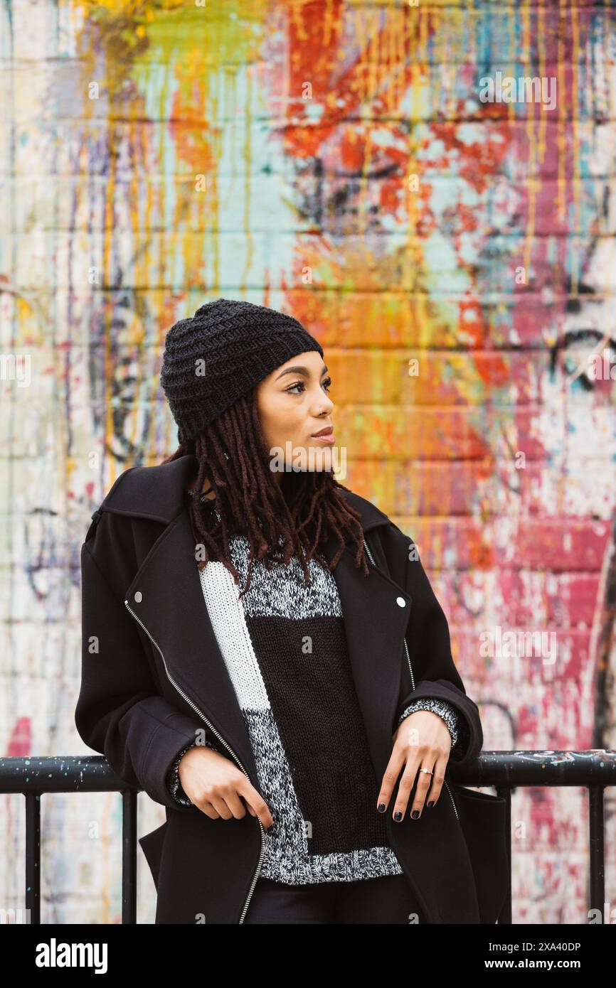 Portrait of a young woman with dreadlocks and wearing a hat, standing ...