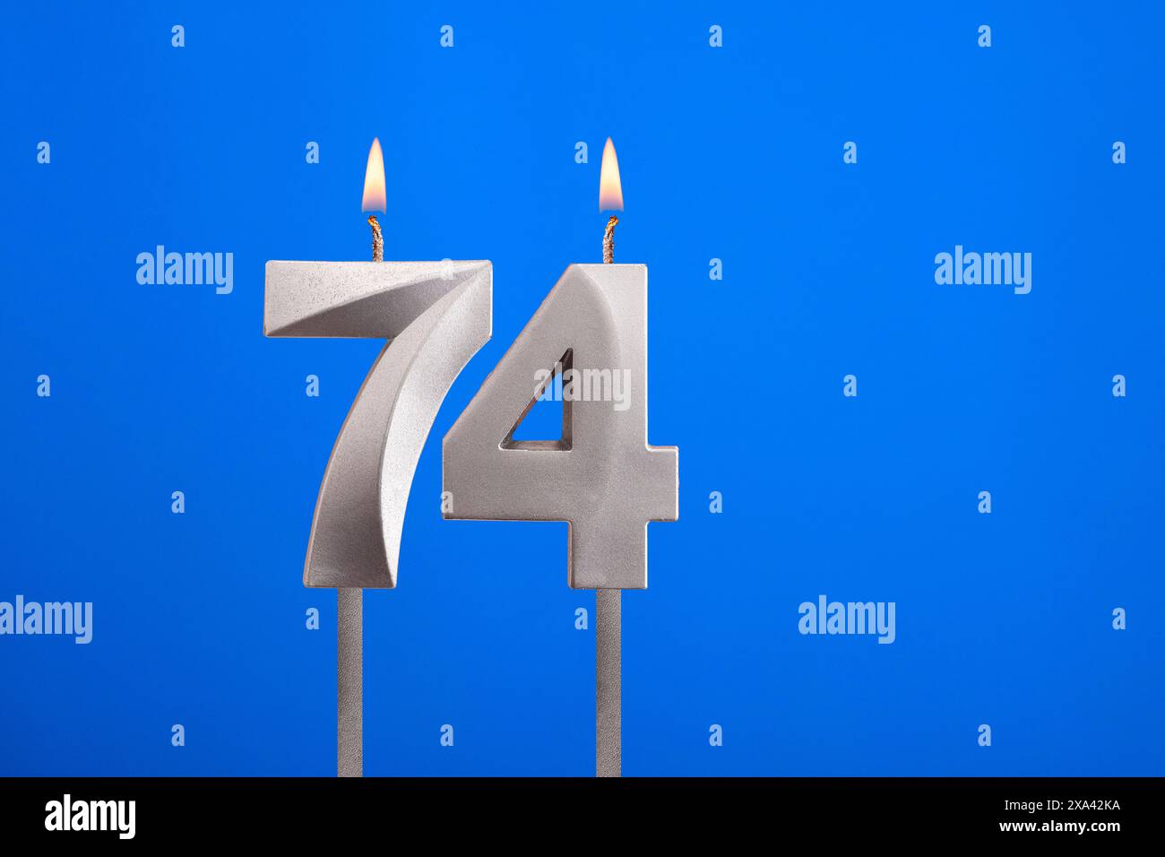 Birthday number 74 - Candle lit on blue background Stock Photo - Alamy