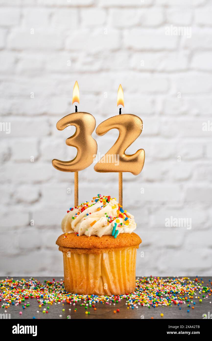 Cupcake with number 32 birthday candle - White block wall background ...
